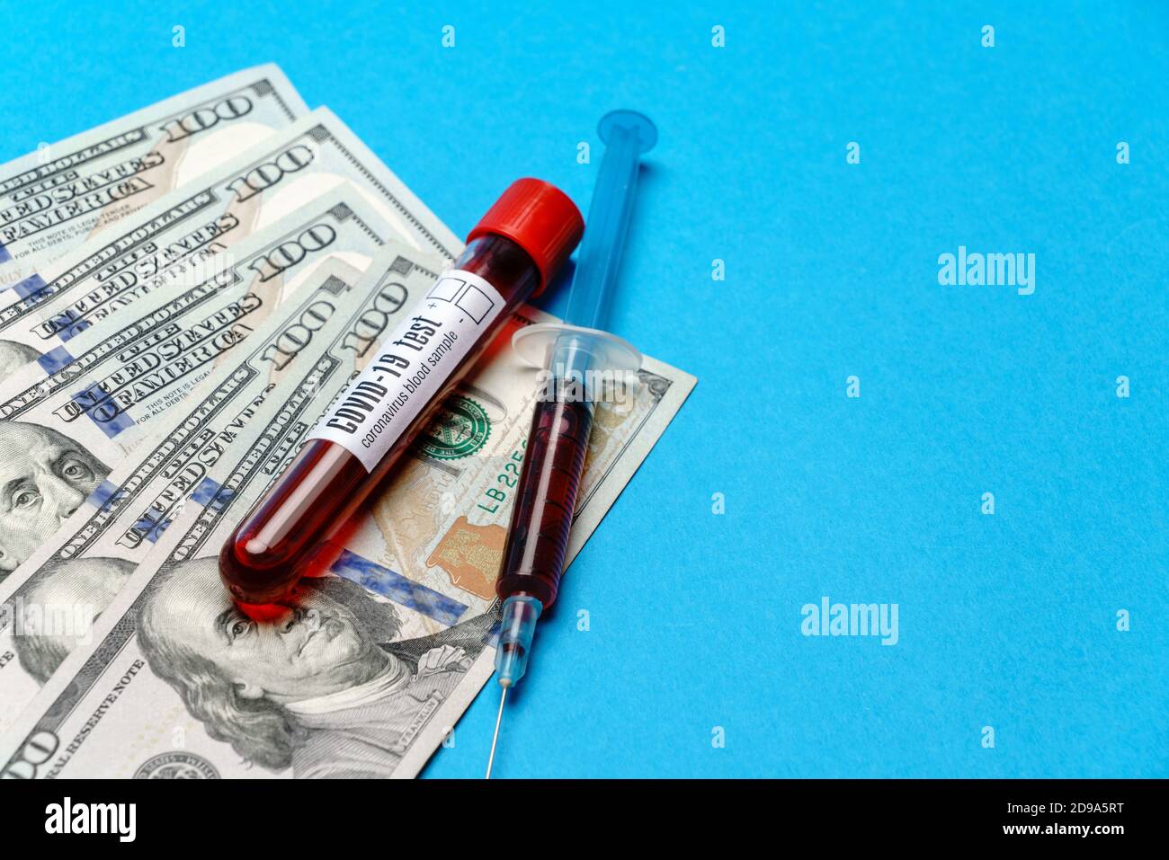 Close up 100 US dollar bills and blood sample in test tube over blue ...