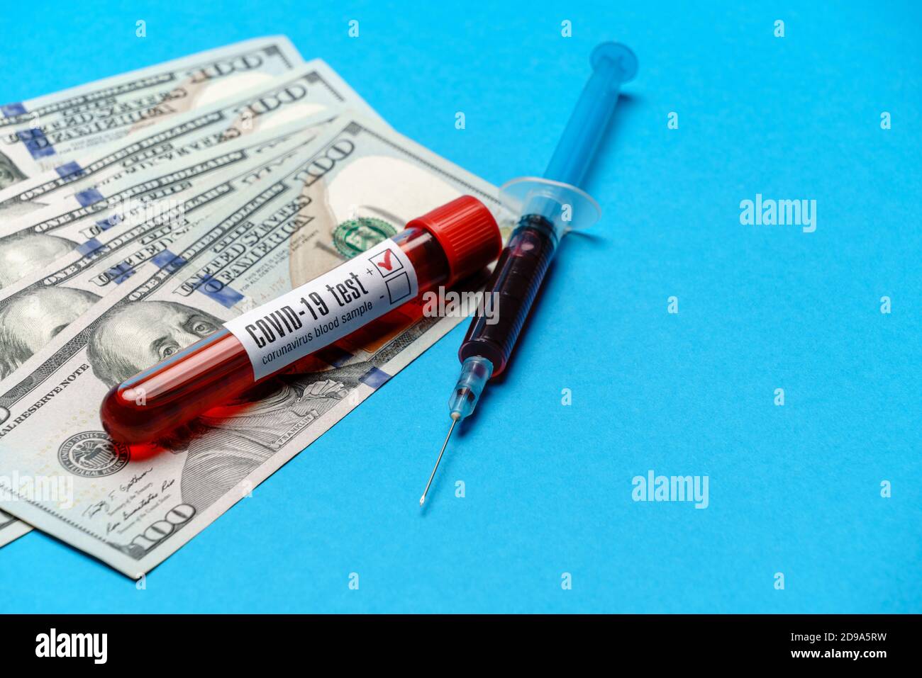 Close up 100 US dollar bills and blood sample in test tube over blue ...