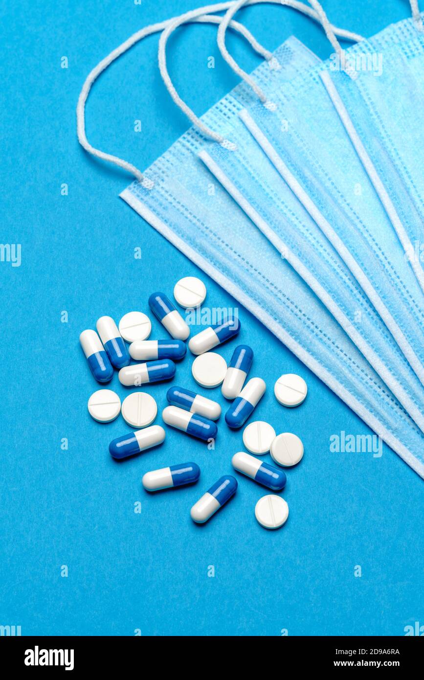 Protective medical face masks and pills on a blue background - Top view ...