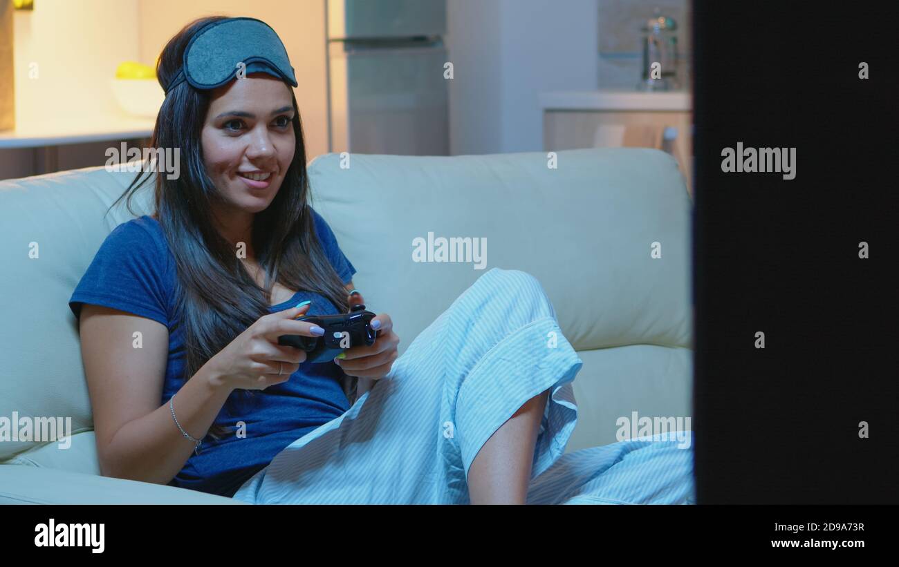 Woman sitting on sofa playing video games, smiling relaxing enjoying ...