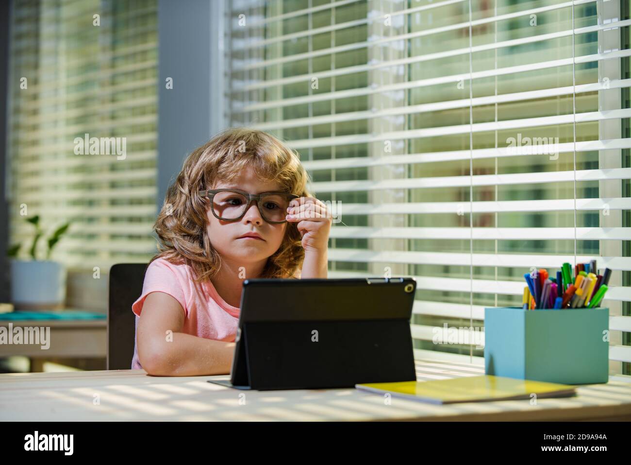 Kid schoolboy in glasses, smart pupil using tablet at home, online ...
