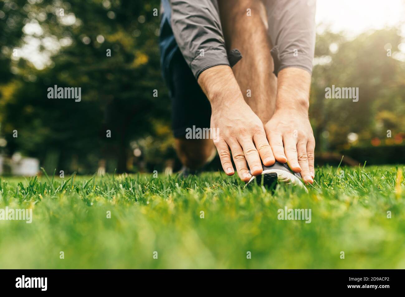 runner stretching in the park before the run, hands and feet in closeup ...