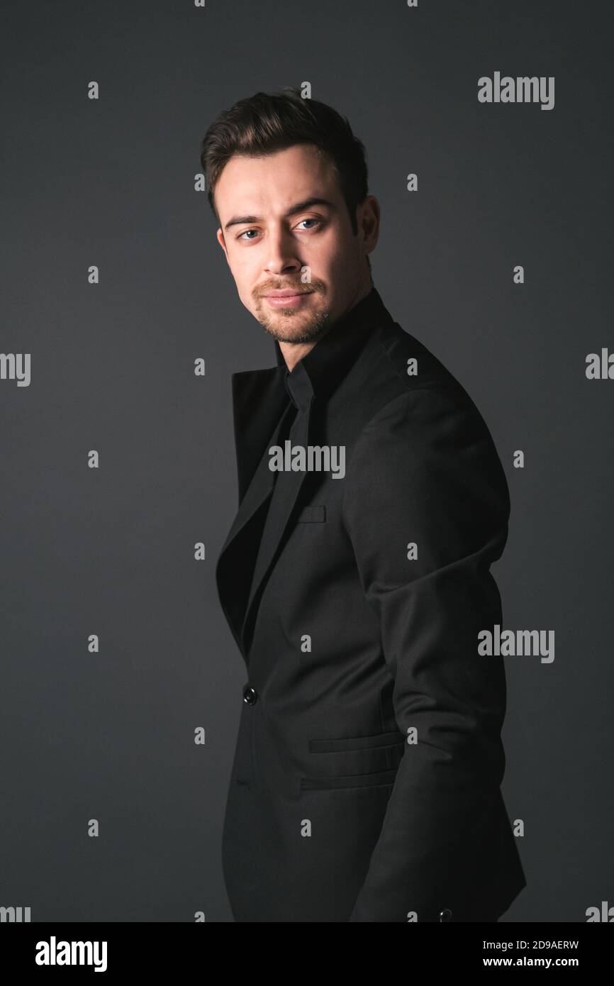 Studio portrait of a young caucasian man in a black blazer, looking at ...
