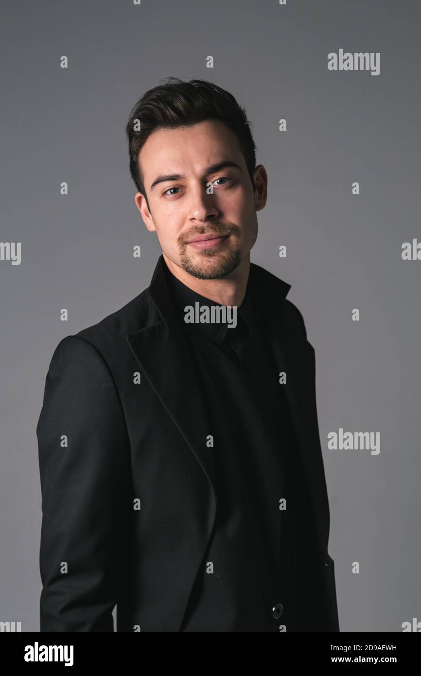 Studio portrait of a young caucasian man in a black blazer, looking at ...