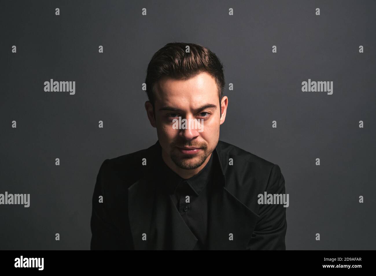 Studio portrait of a young caucasian man in a black jacket, seriously ...