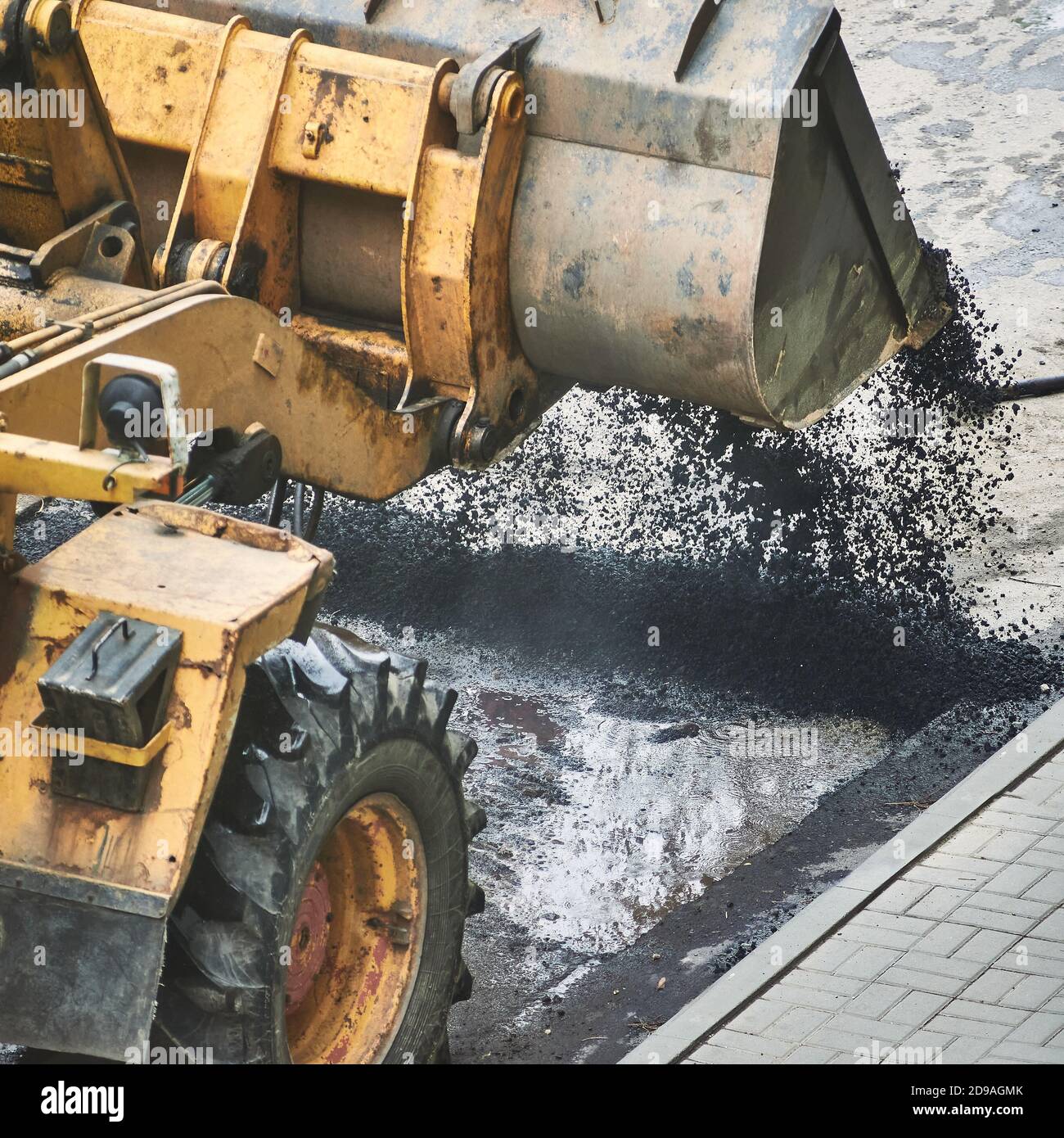 hot smoking asphalt excavator ejects from the bucket. paving with a ...
