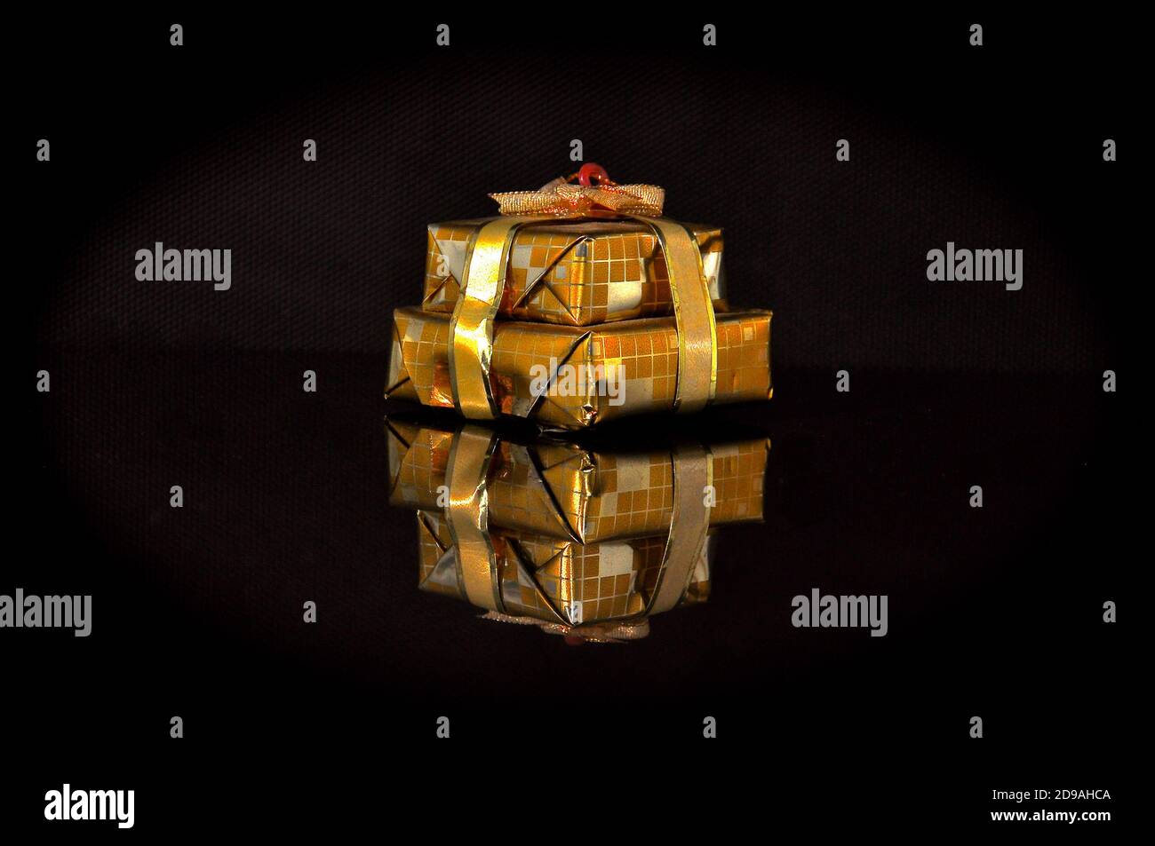 Small cuboid parcels gift wrapped in gold foil wrapping paper and shiny ...