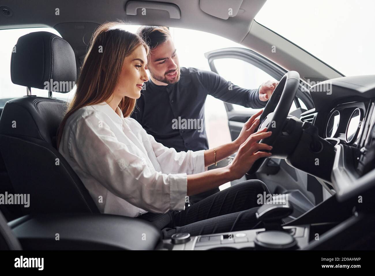 Woman testing car by help of male assistant indoors in the salon Stock ...