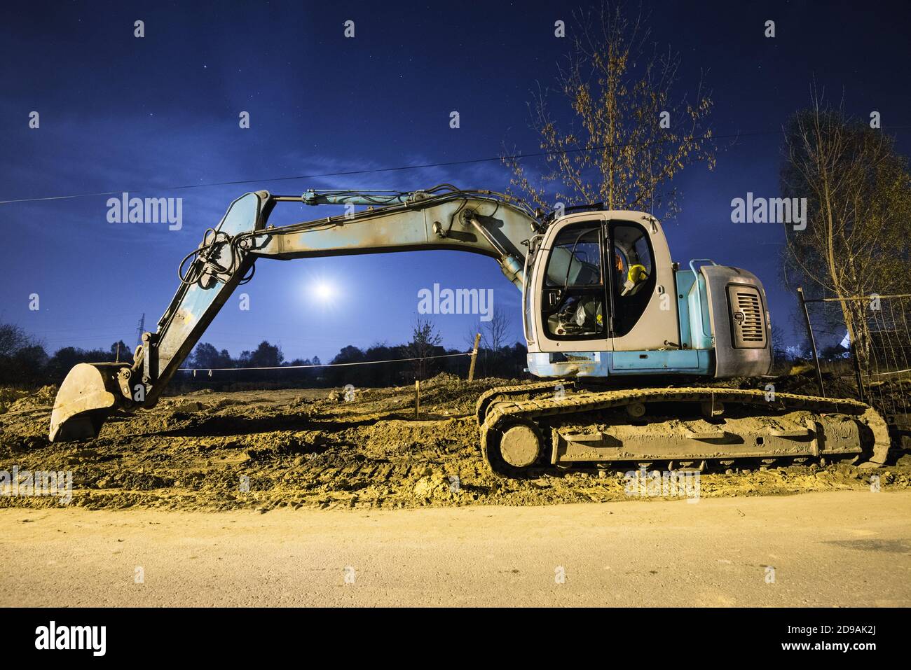Blue excavator digger working at night on the street Stock Photo - Alamy