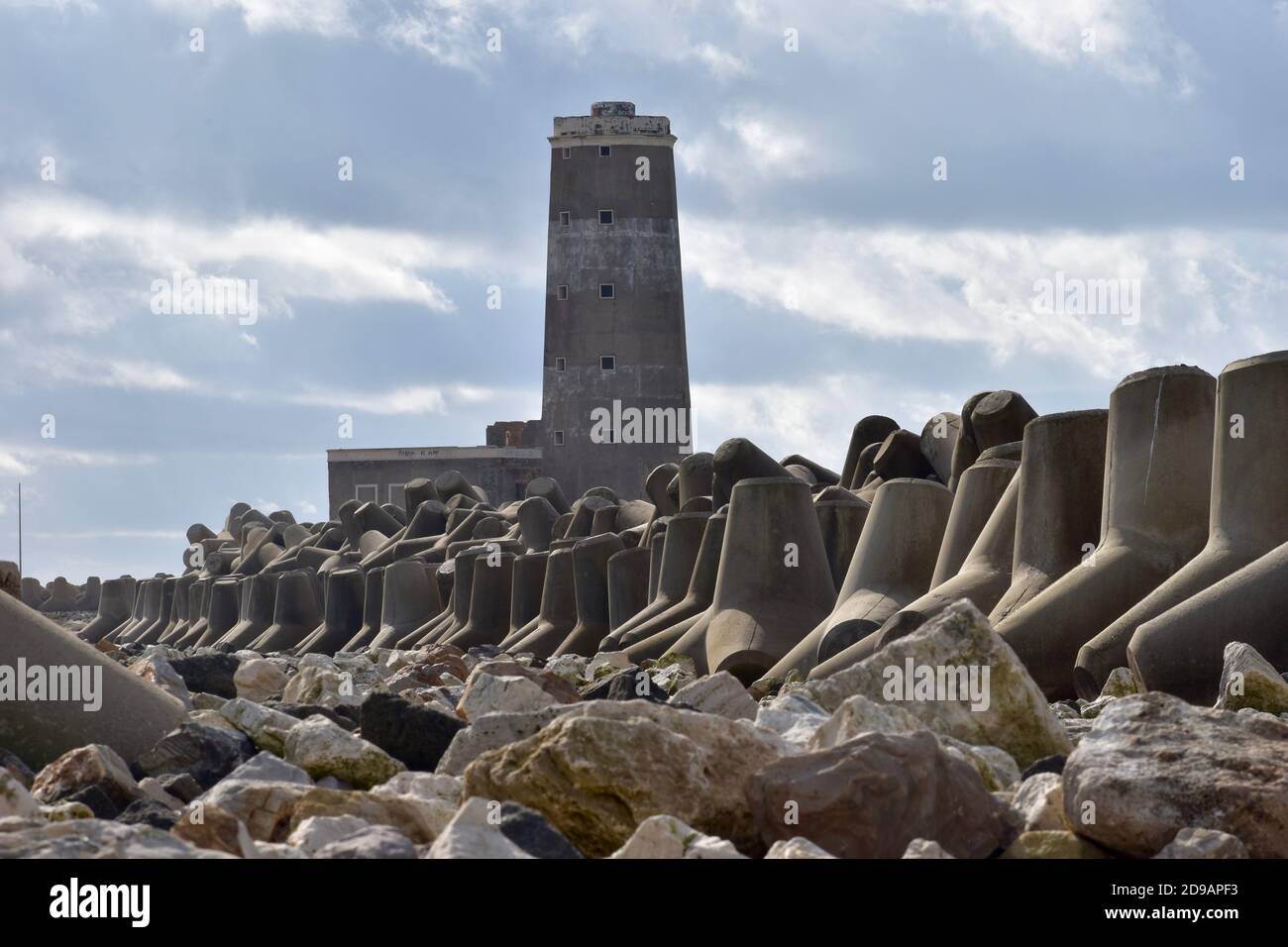 Old wreck of a lighthouse near Rome. There's a cliff of giant manmade ...