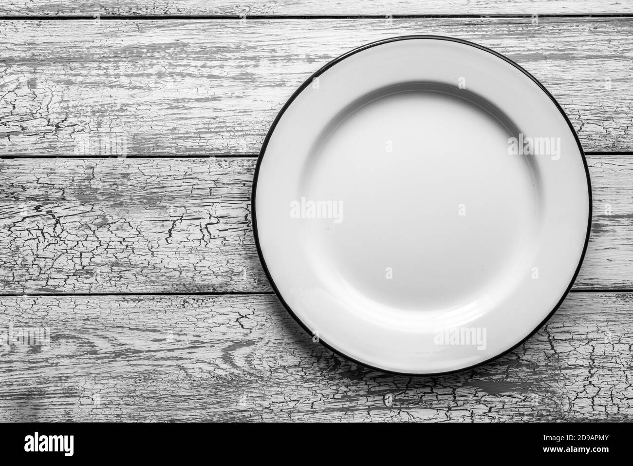 Metal white plate with blue border on wooden table Stock Photo - Alamy