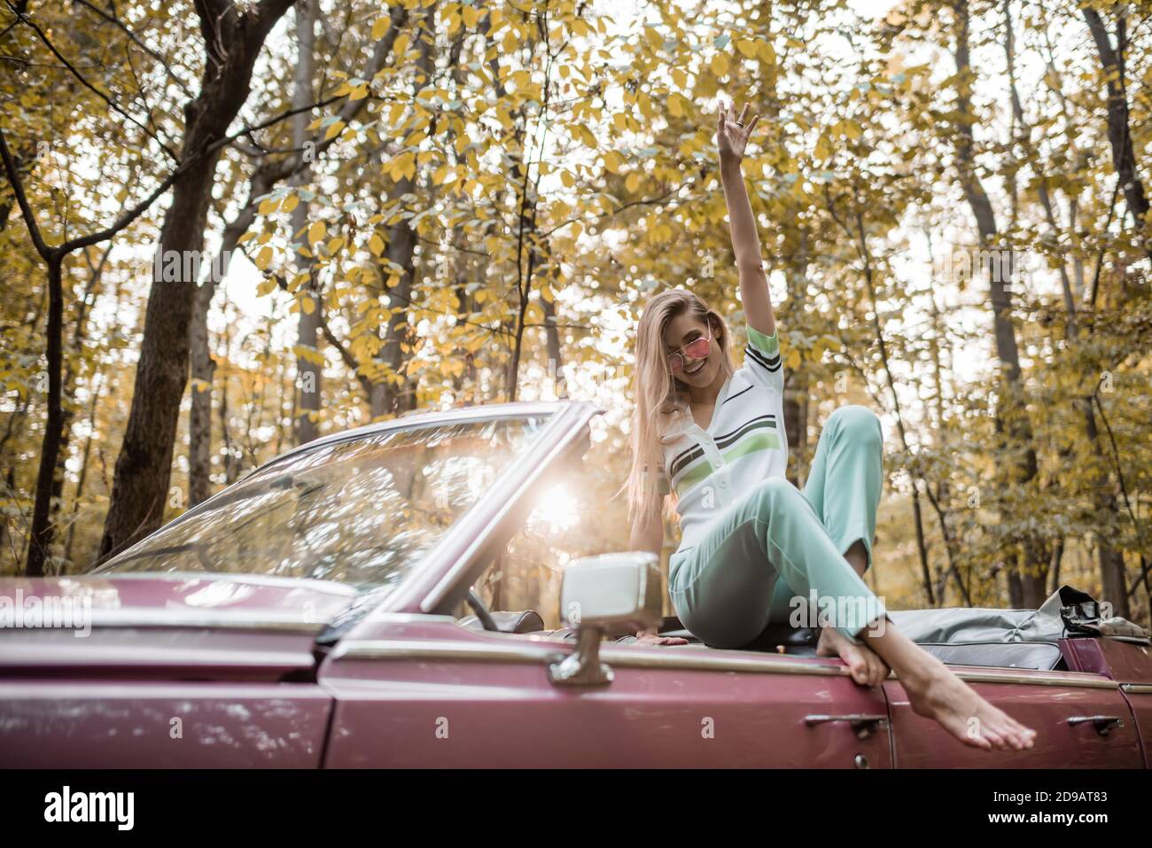 joyful barefoot woman looking at camera while posing with hand in air ...