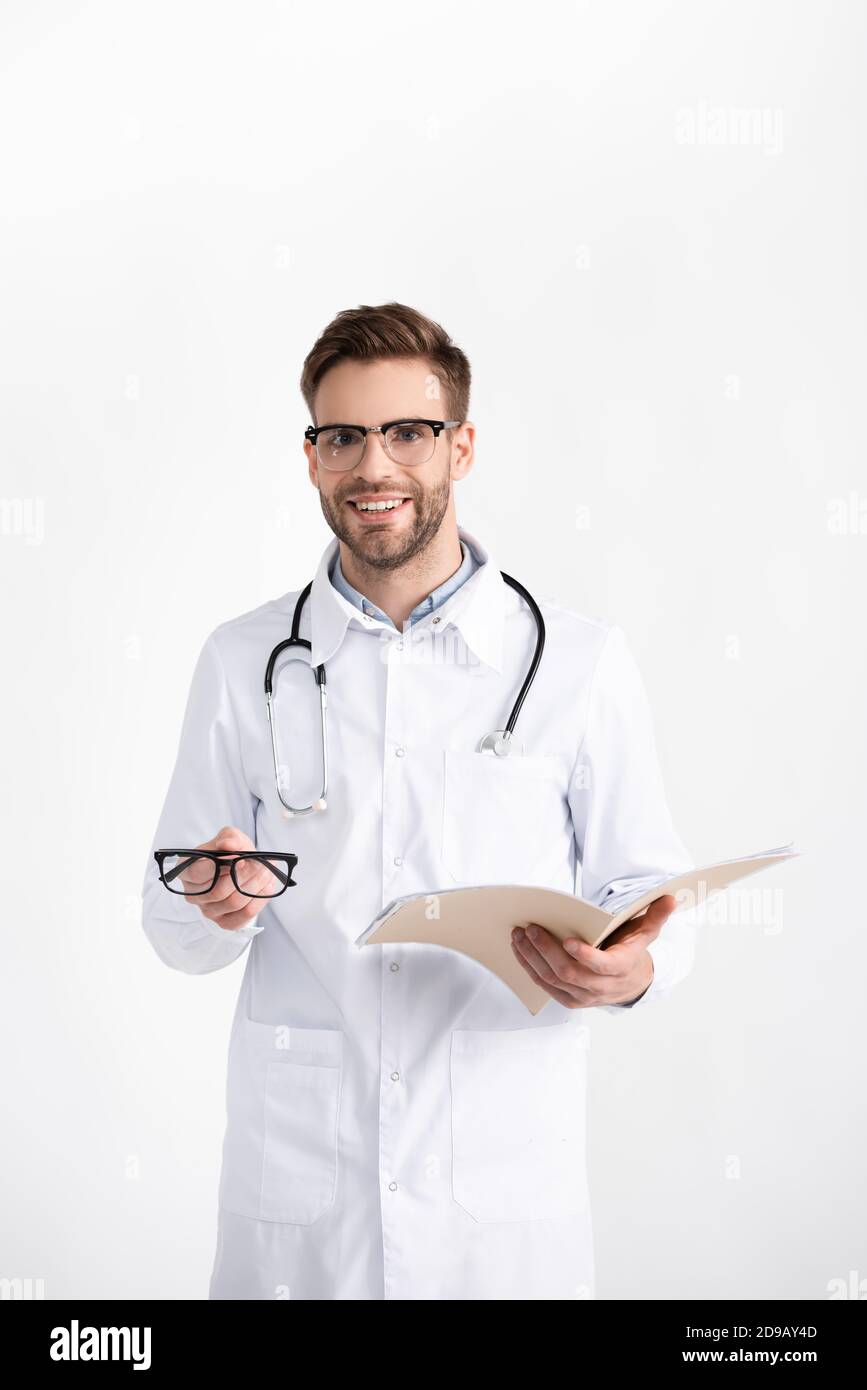 Front view of smiling doctor with stethoscope holding eyeglasses and ...