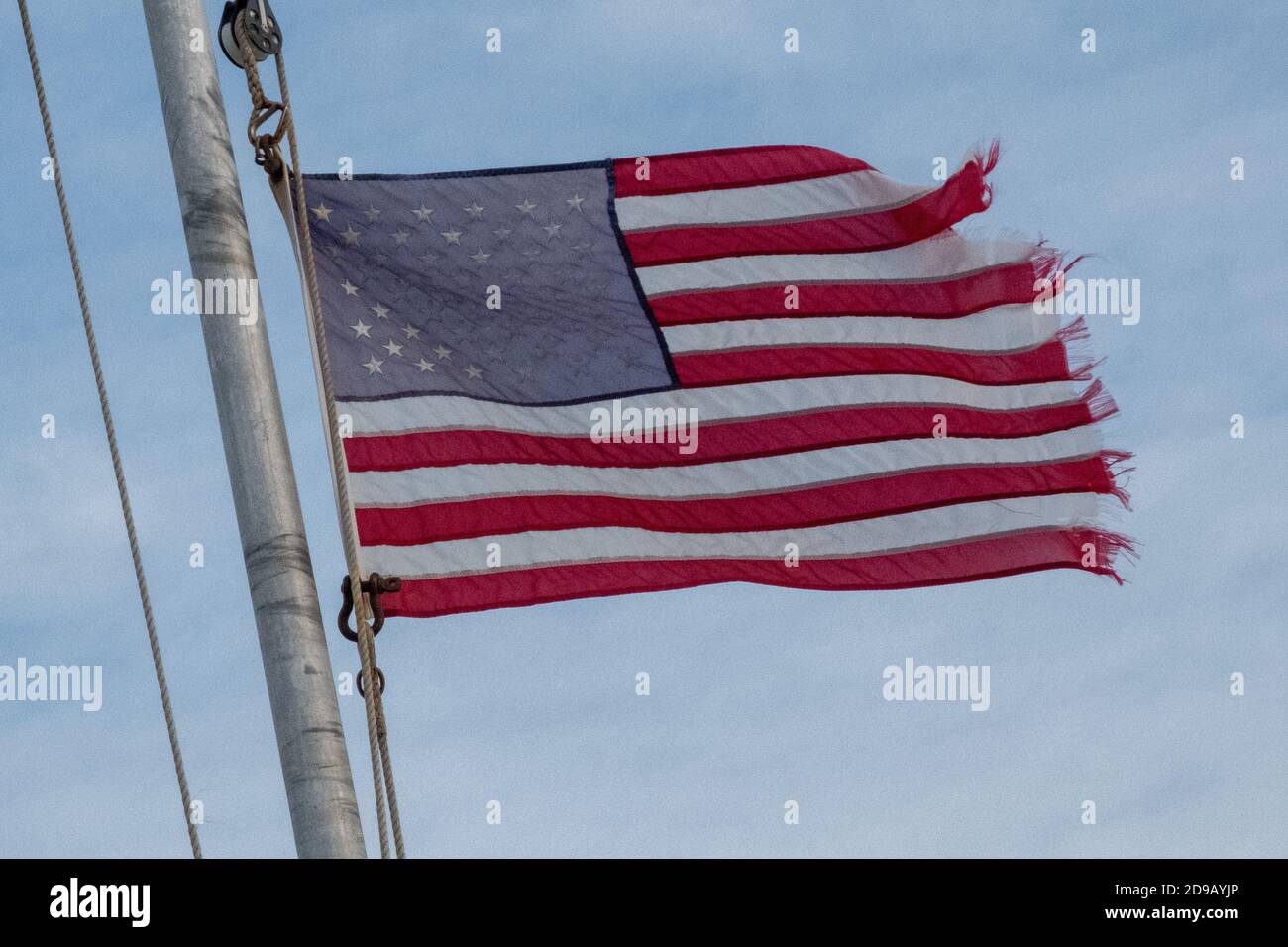 Wind tattered and frayed stars and stripes United States flag flying ...