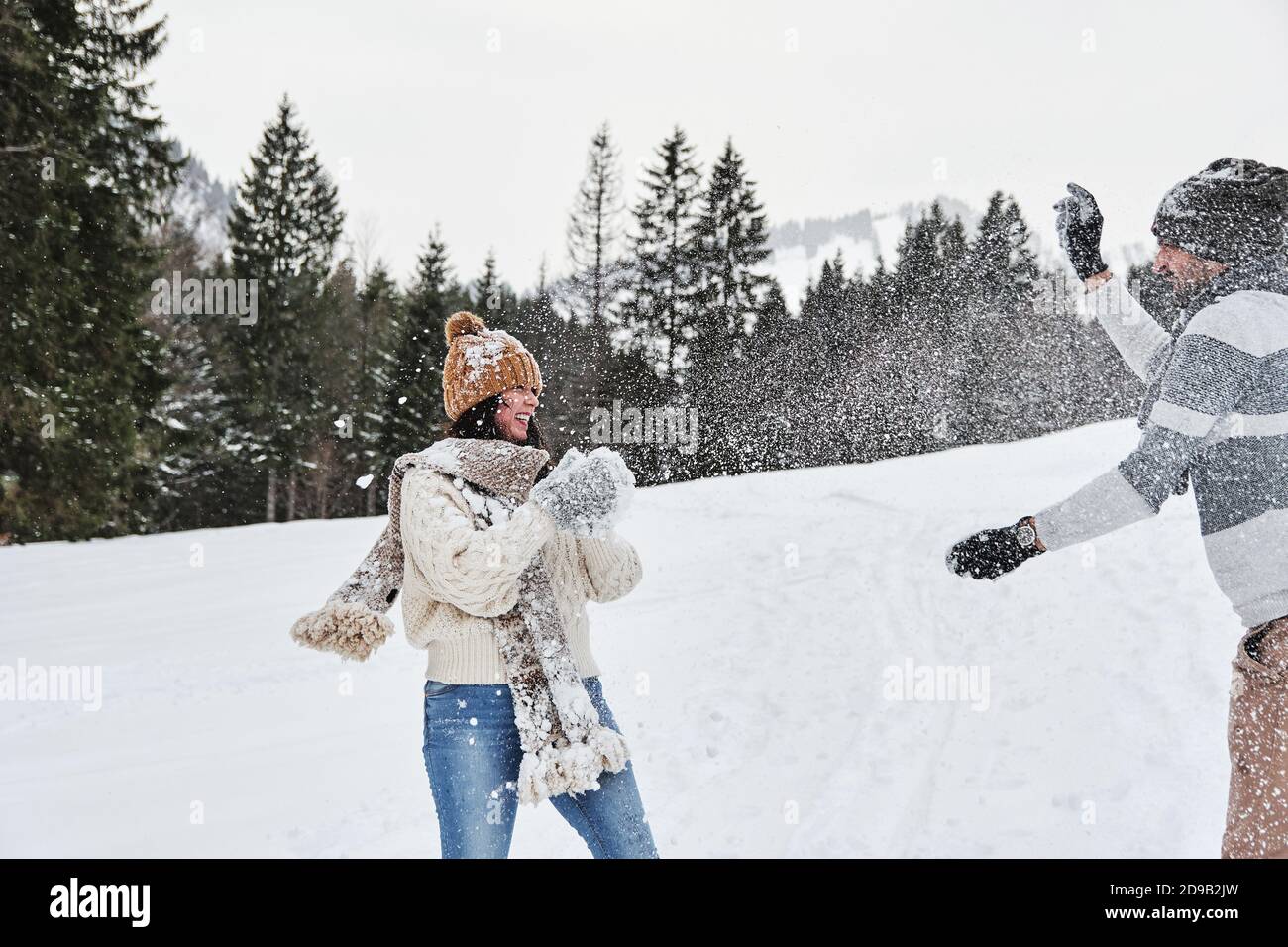 Cheerful young Caucasian couple having a snowball fight in the snow ...
