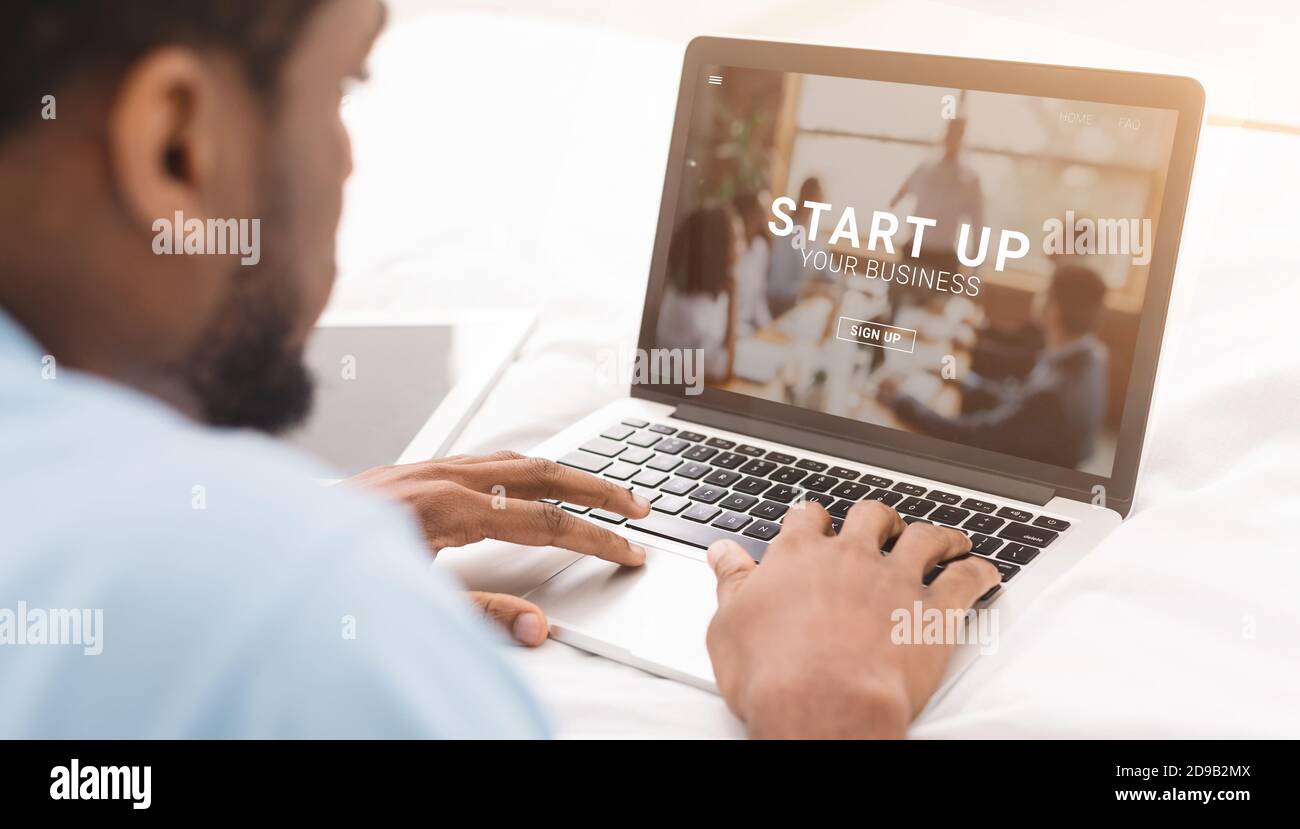 African American entrepreneur working on laptop computer with START UP ...