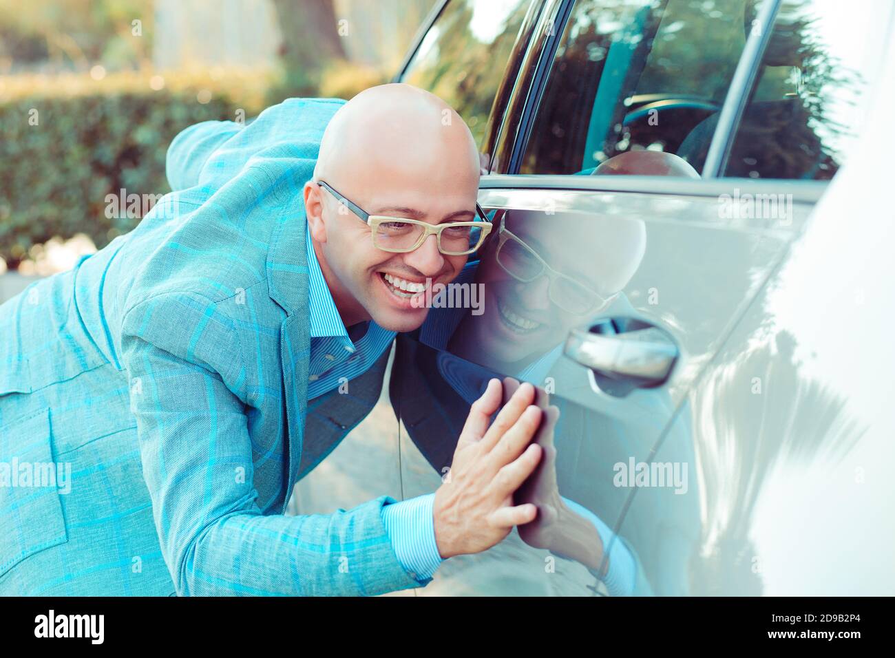 Happy excited young bald italian man driver embracing petting his car ...
