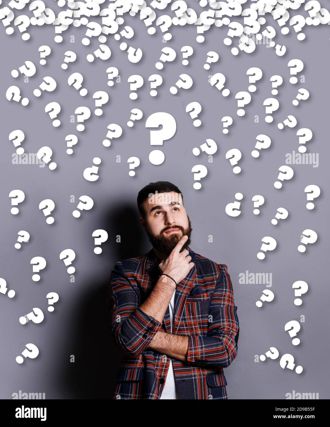 Bearded Caucasian guy looking up and thinking over grey background with ...