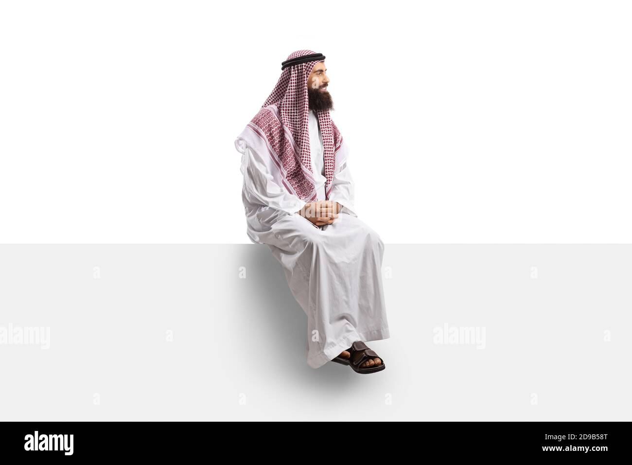 Saudi man in a thobe sitting on a blank panel and looking to the side ...