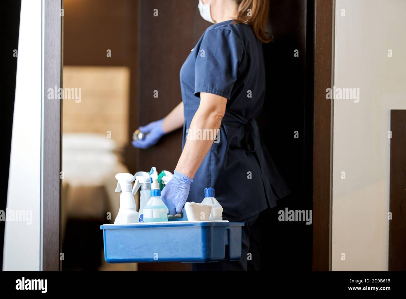 Back view of housemaid keeping all necessary cleaning and disinfection ...