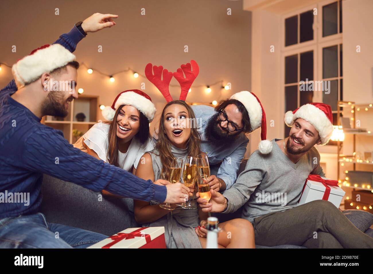 Happy friends in holiday hats having fun during Christmas celebration ...
