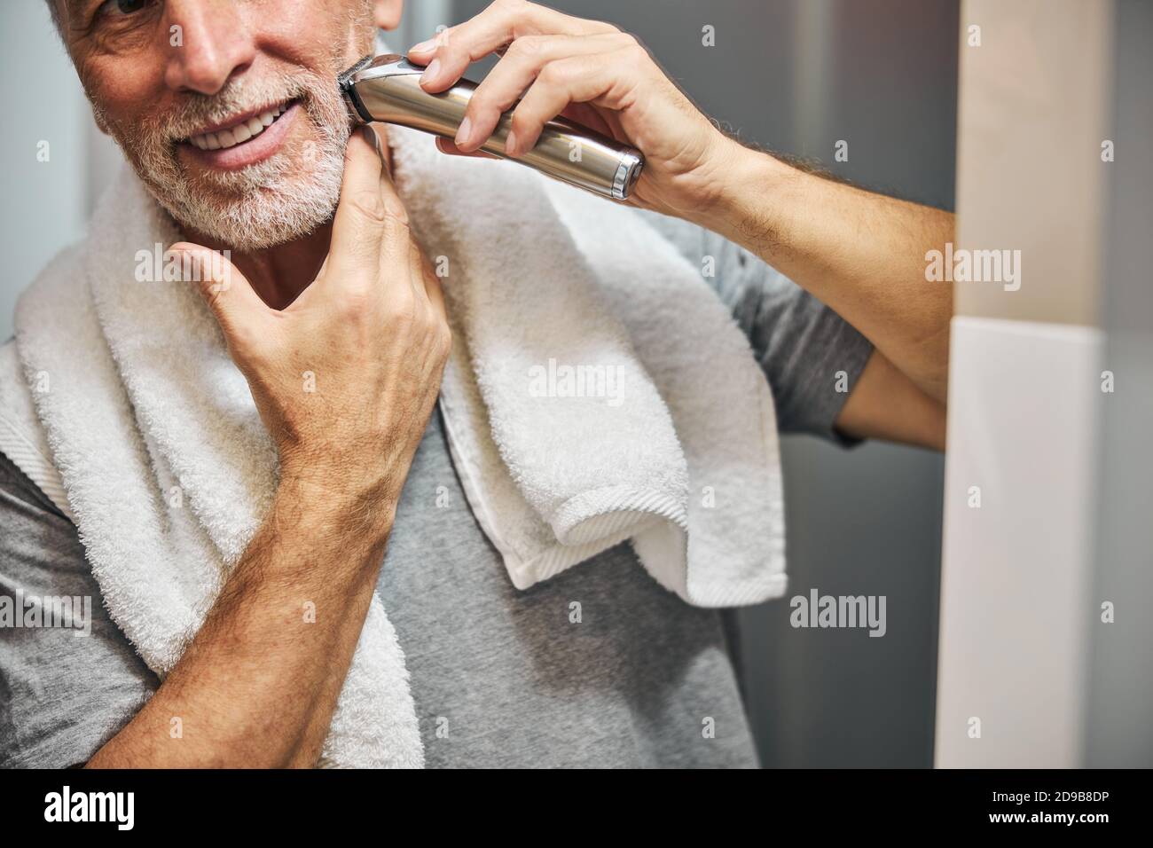 Senior man smiling while shaving his beard with electric device Stock ...