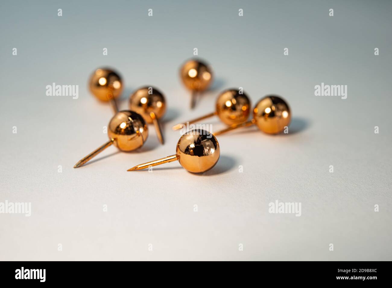 group of gold-colored chalkboard pins lie on a light background ...