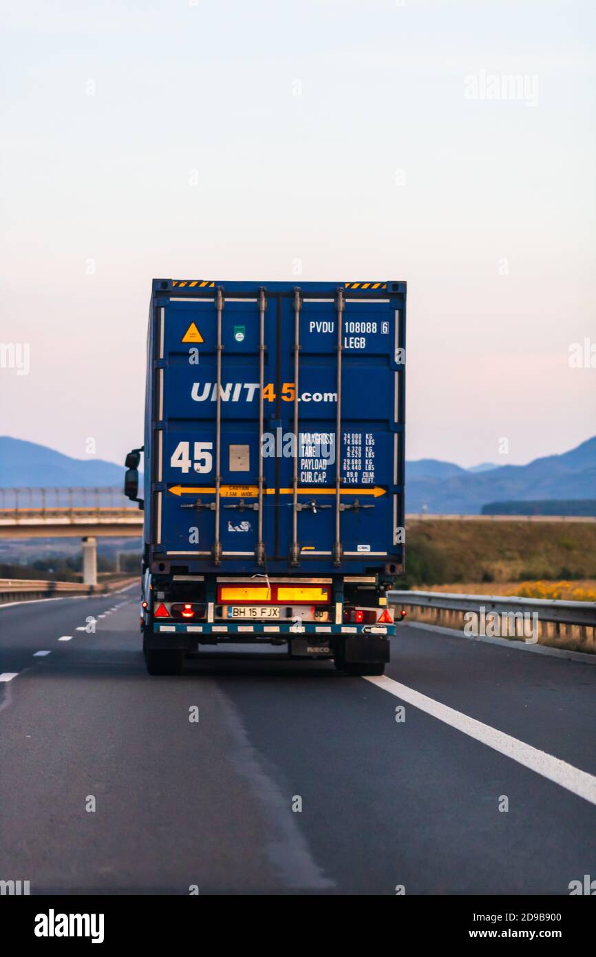 Back view of loaded European truck in motion on asphalt road ...