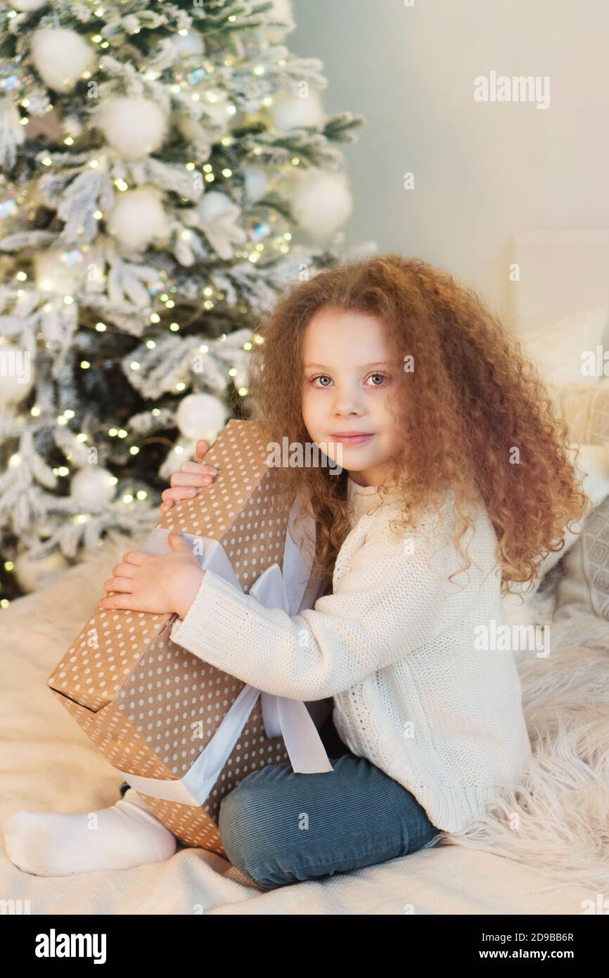 Christmas morning, cute little girl with curly hair looking at the ...
