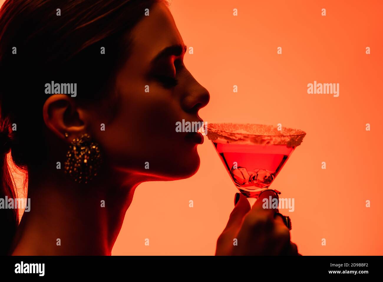 side view of young woman with closed eyes drinking margarita cocktail ...