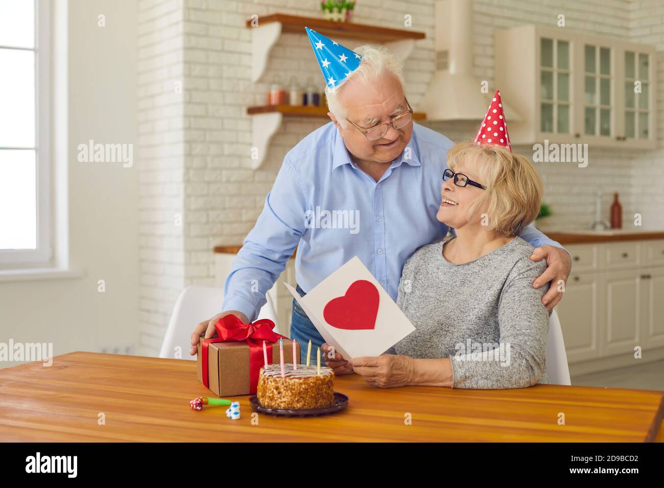Happy loving senior couple in party hats having quiet birthday ...