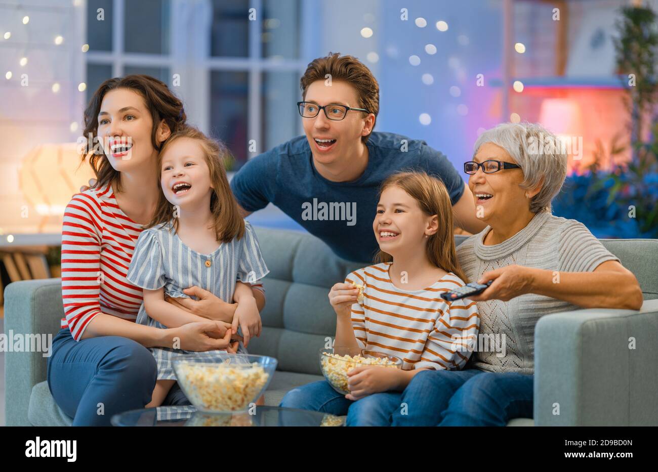 Happy family watching projector, TV, movies with popcorn in the evening ...