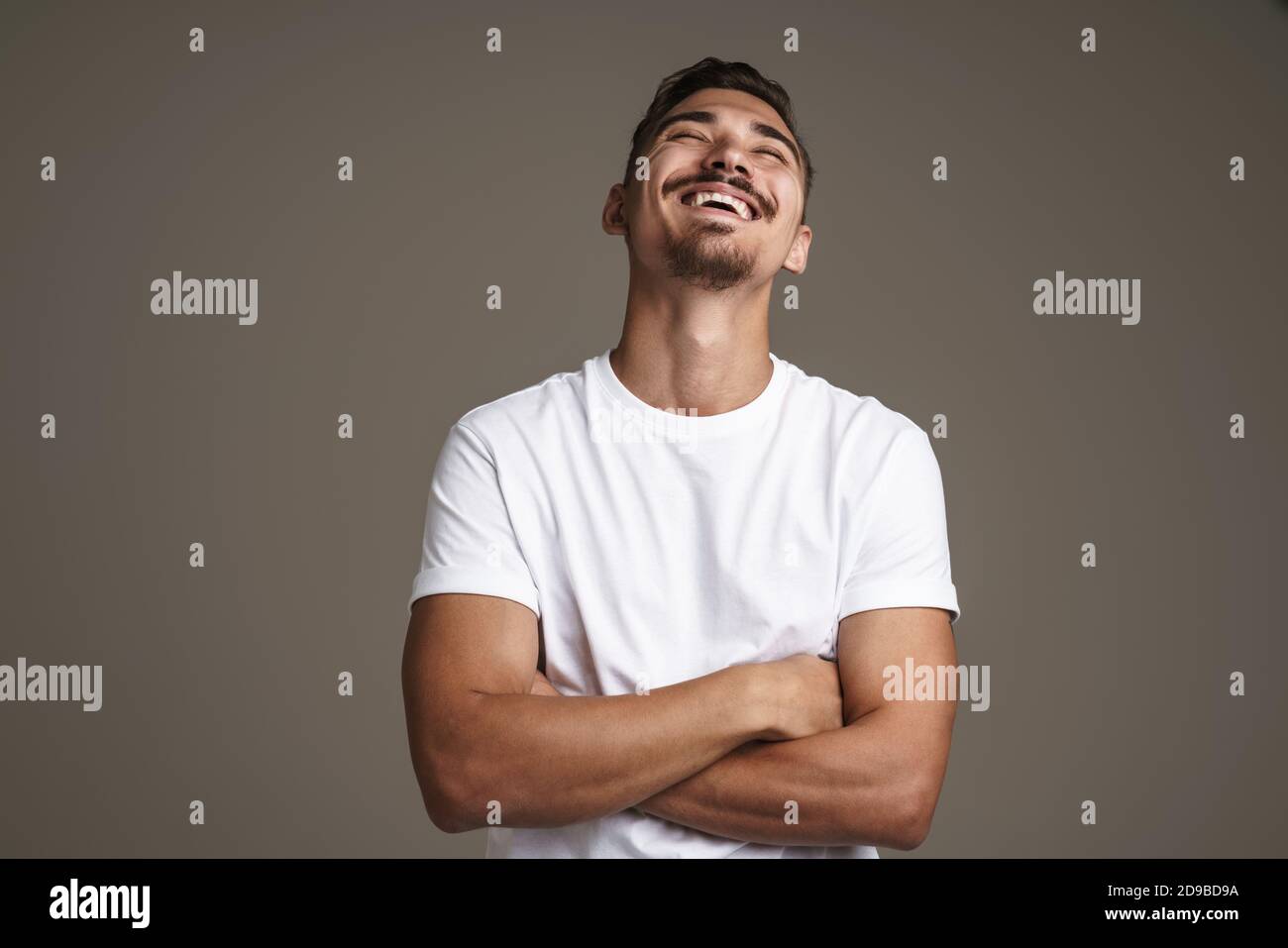 Image of laughing unshaven guy posing on camera with arms crossed ...