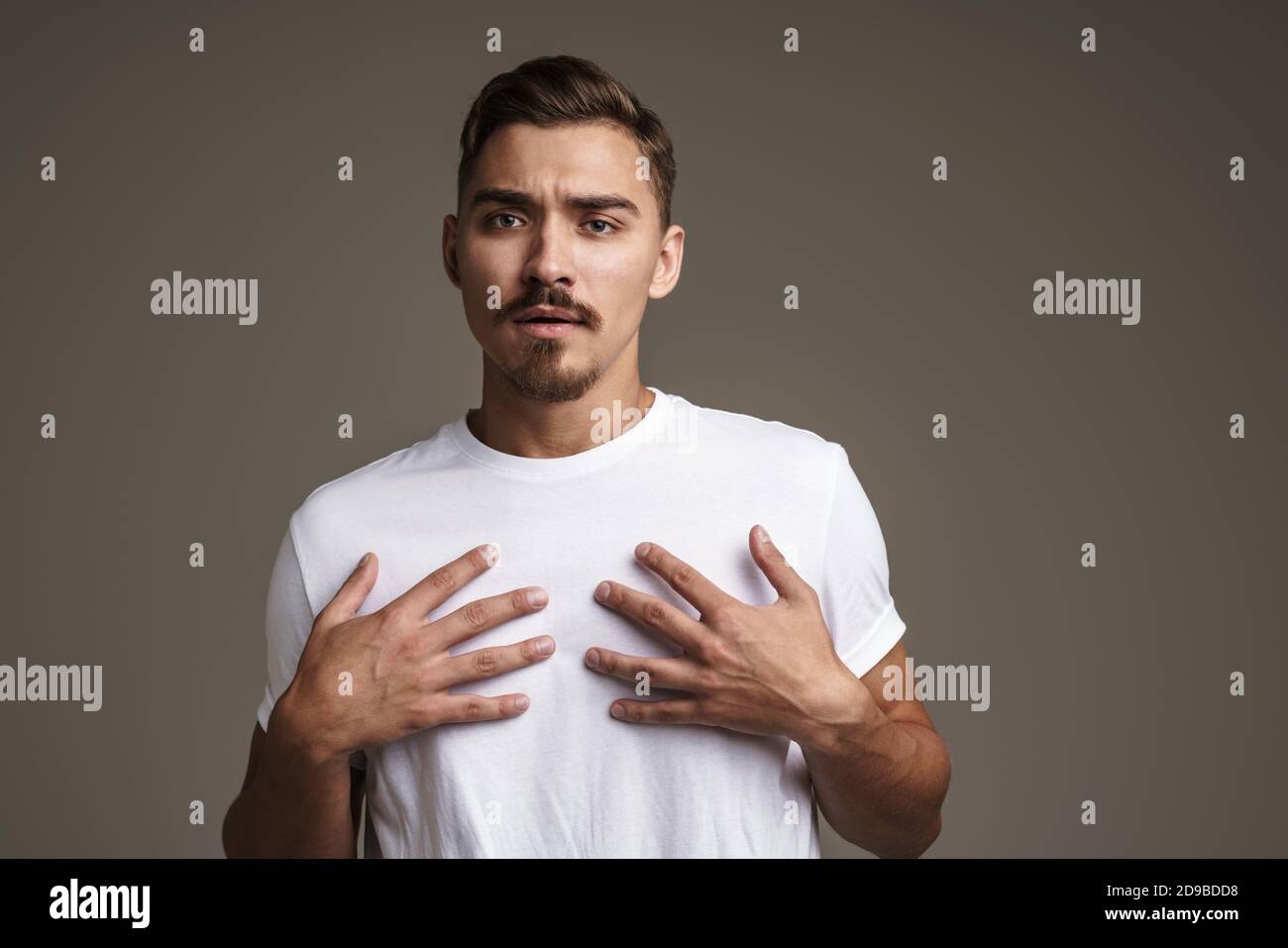 Image of confused unshaven guy posing with hands on his chest isolated ...