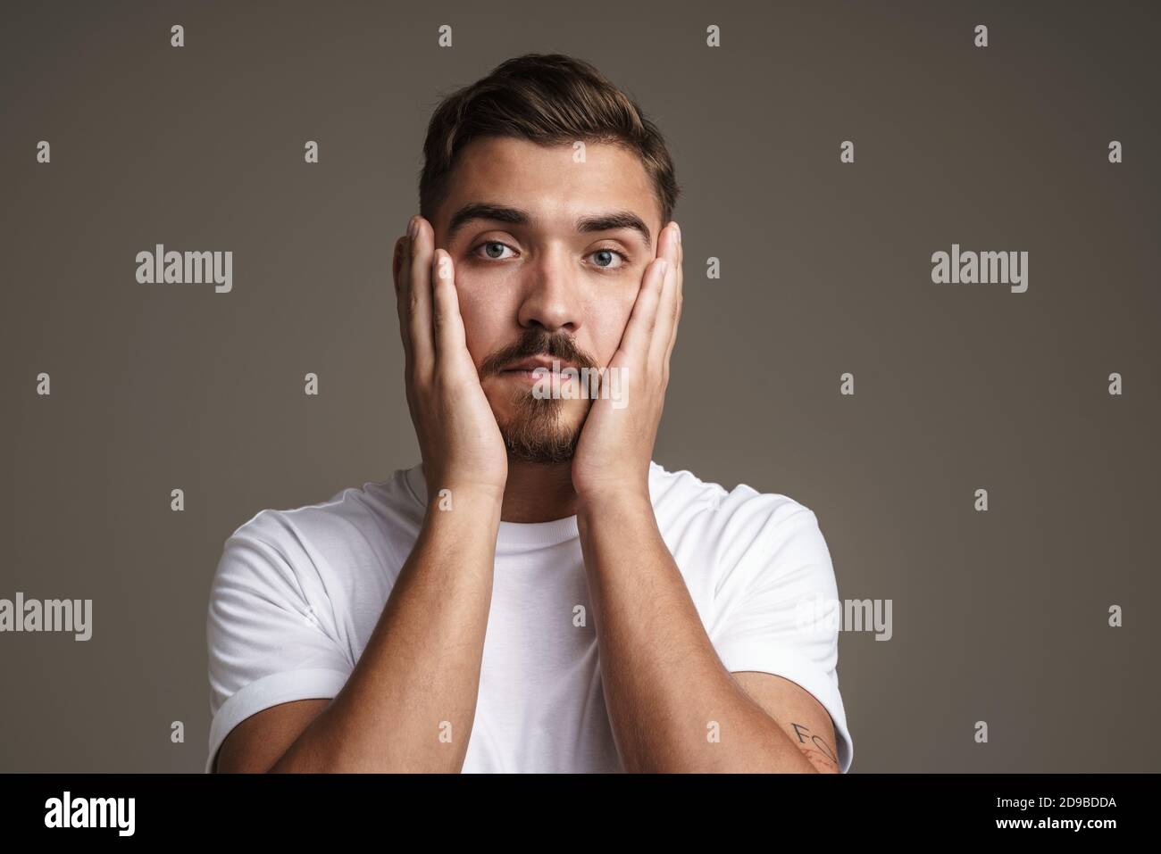 Image of handsome unshaven guy posing while grabbing her face isolated ...