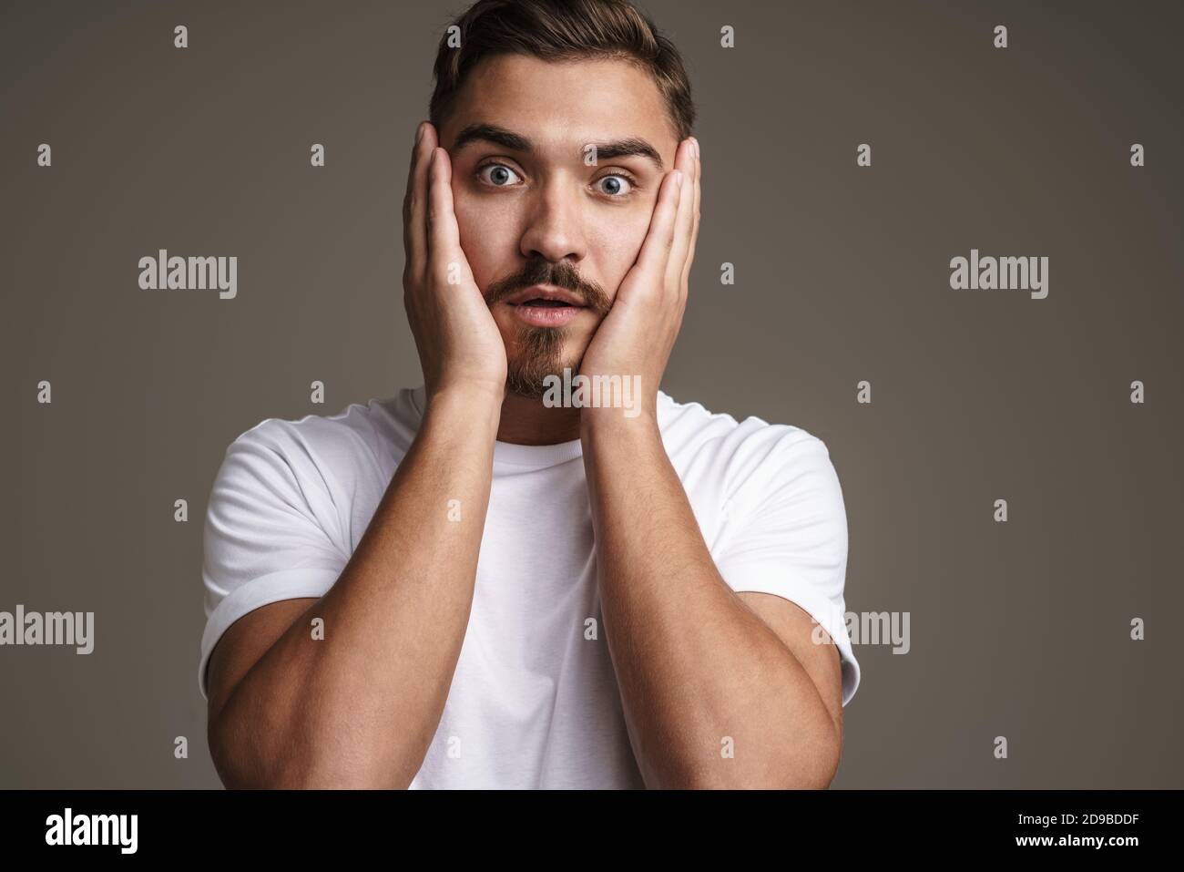 Image of shocked unshaven guy expressing surprise and grabbing her face ...
