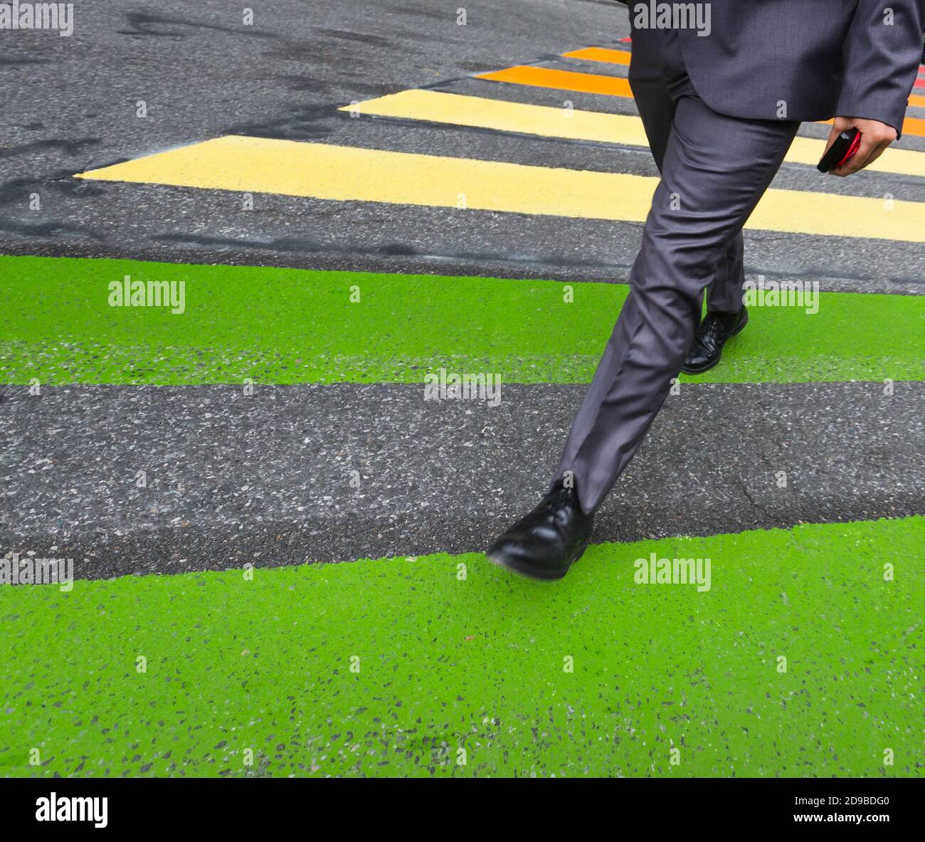 Zebra crossing. Man in a suit with a mobile phone in hand cross street ...