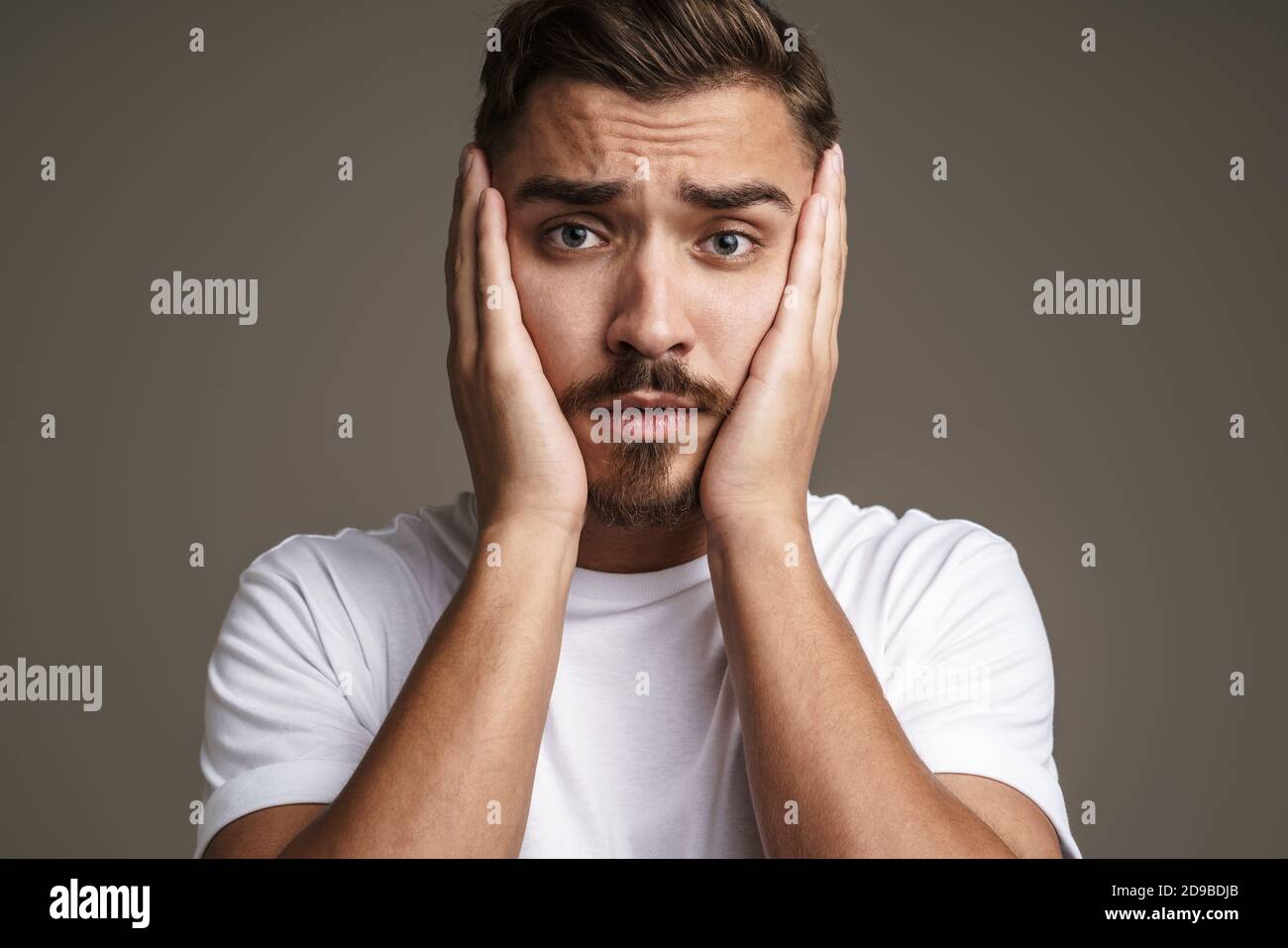Image of unhappy unshaven guy posing and grabbing her face isolated ...