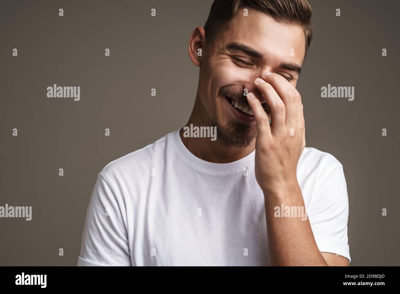 Image of joyful unshaven guy laughing and covering his face isolated ...