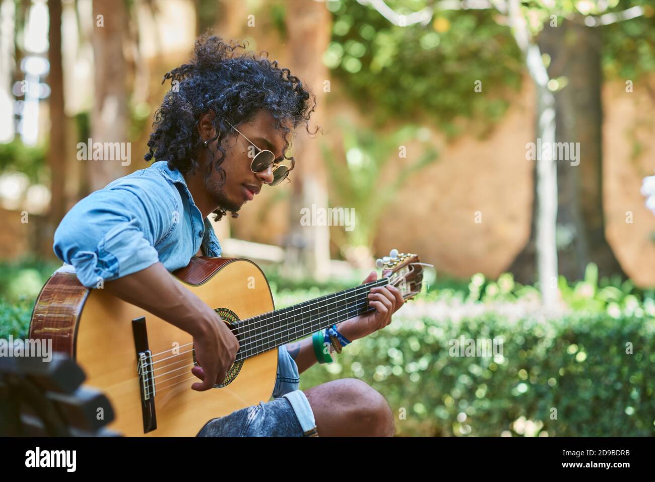 Young musician with classical guitar playing under the shade of some ...