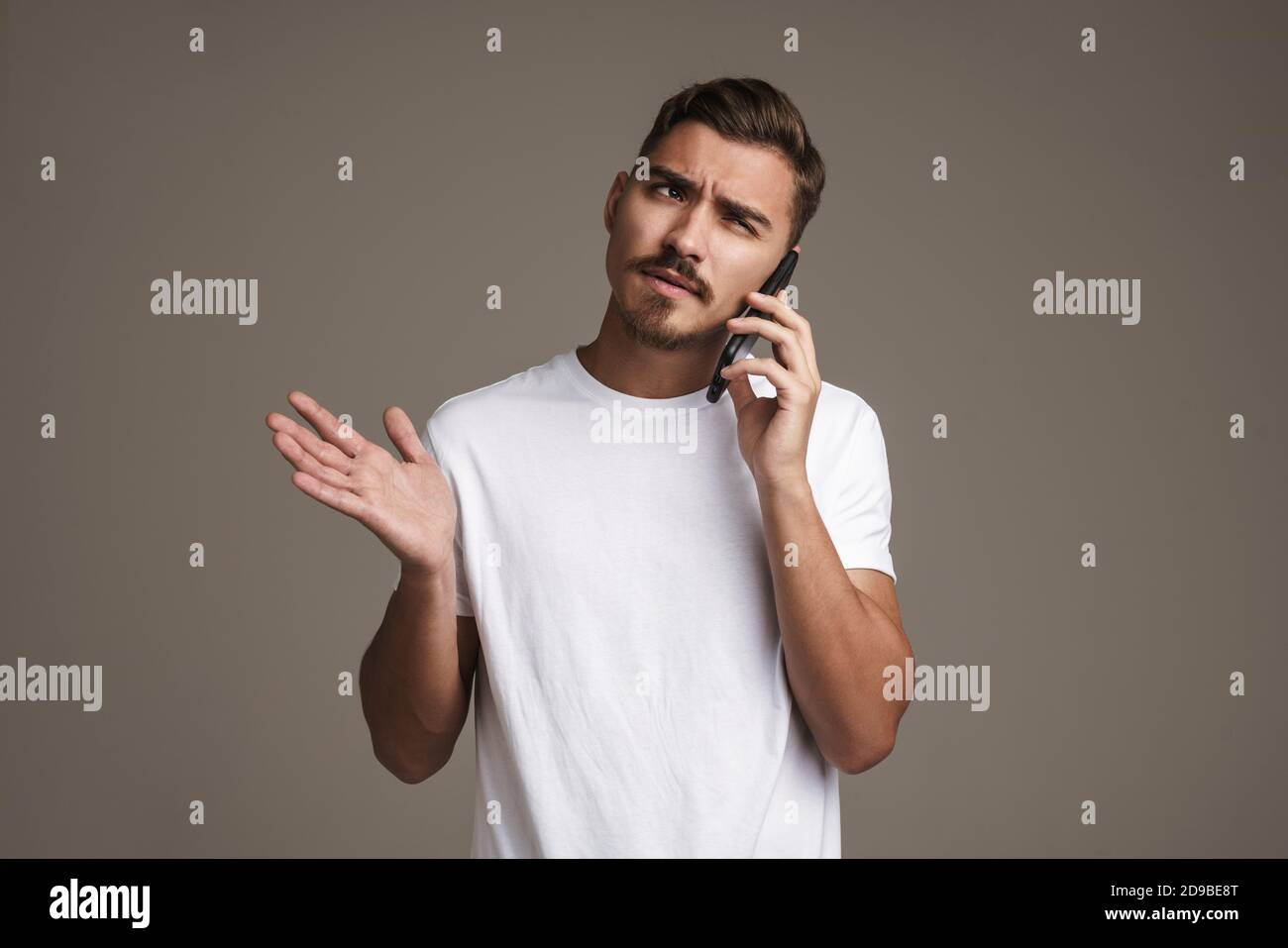 Image of confused guy showing gesturing while talking on cellphone ...