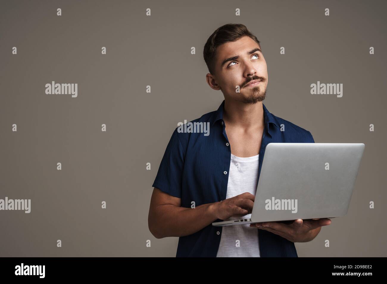 Image of serious handsome guy thinking while using laptop isolated over ...