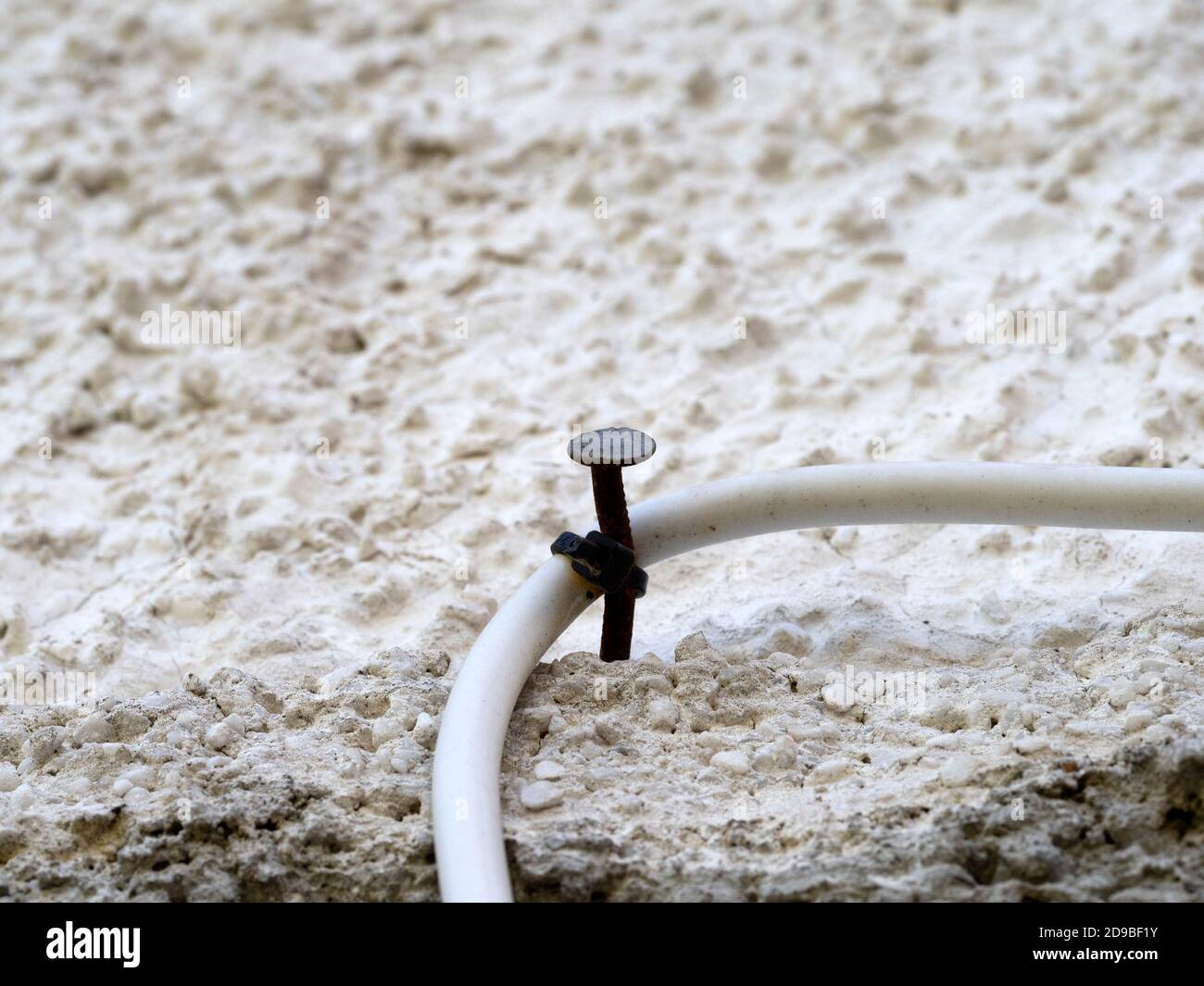 cable and spike on a wall detail Stock Photo - Alamy