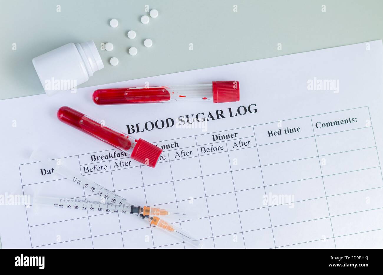 Blood sugar log with blood sample tubes, syringes and pills top view ...