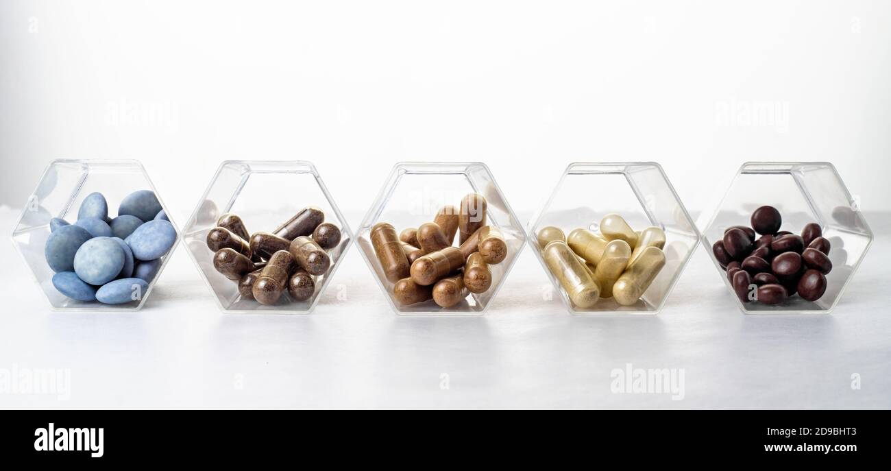 Various medical capsules and tablets in hexagonal transparent jars ...