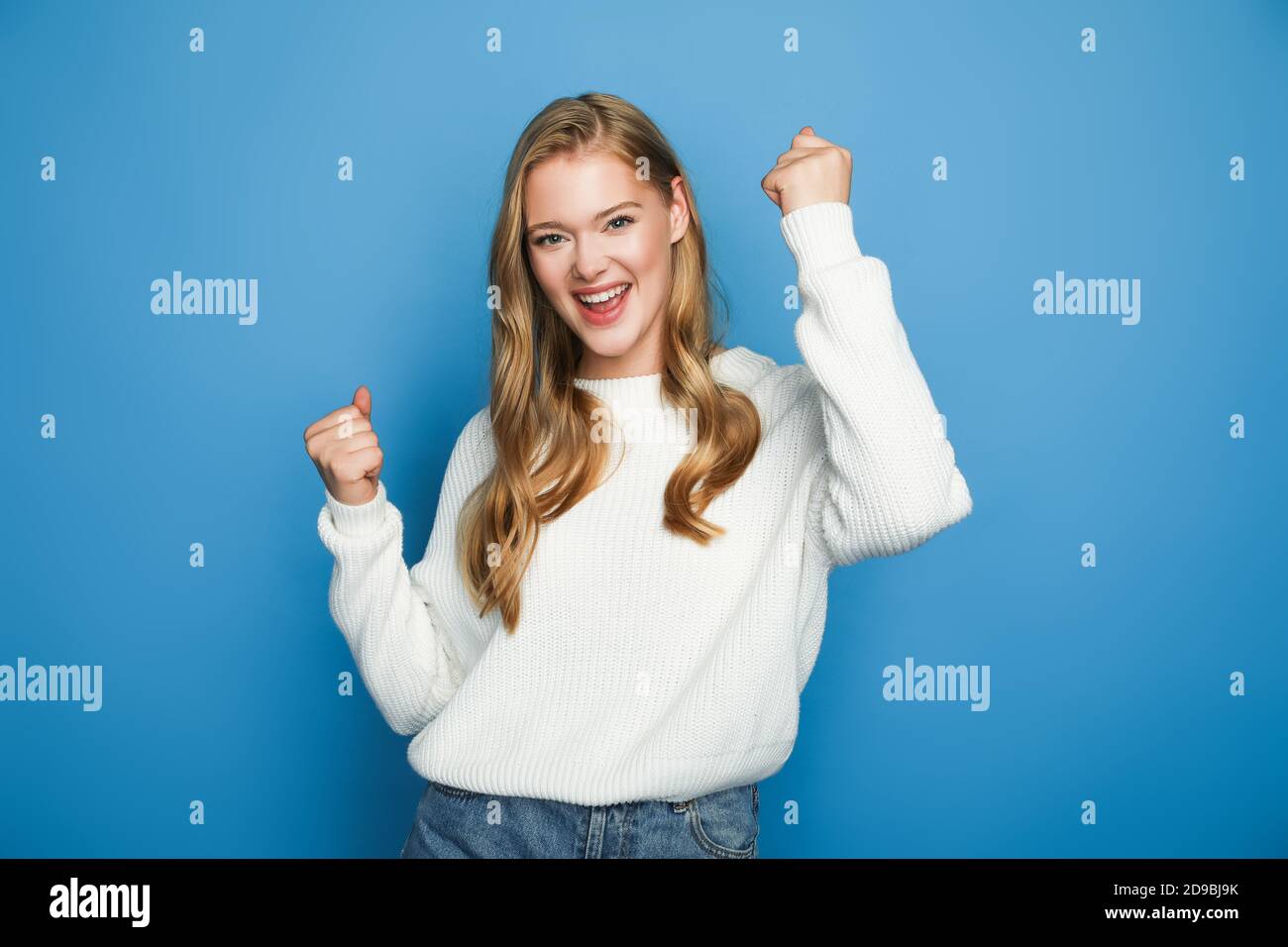 happy blonde beautiful woman in sweater showing yeah gesture isolated ...