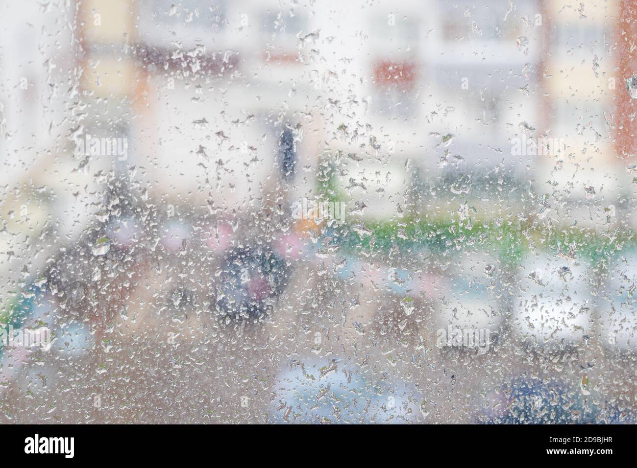 View through a rainy window on a blurred house and car parking. Bad ...
