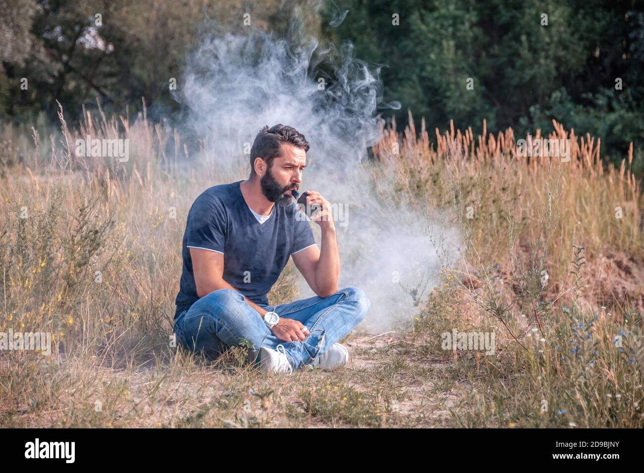 Stylish smoker enjoying an e-cigarette out in the forest. The new ...