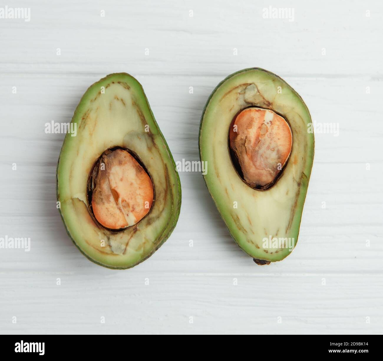 ugly rotten spoiled avocado fruit on white wooden background. Ugly food ...