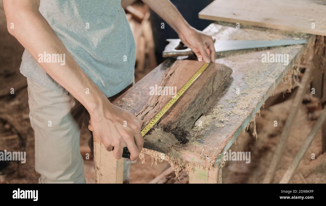 close up carpenter's hand measuring wood using carpenters ribbon ruler ...
